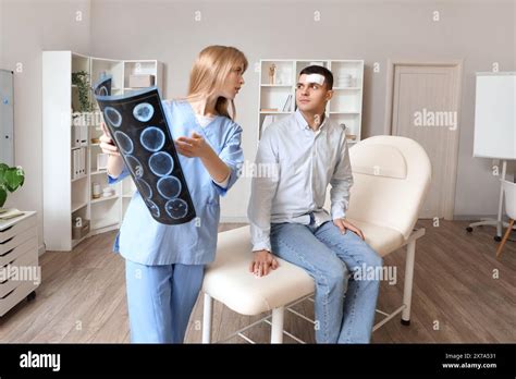 Female Doctor And Man With Brain Concussion Examining Mri Scan In
