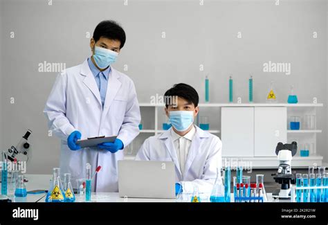 Two Scientists With Face Mask And Gown Working In Laboratory Omicron