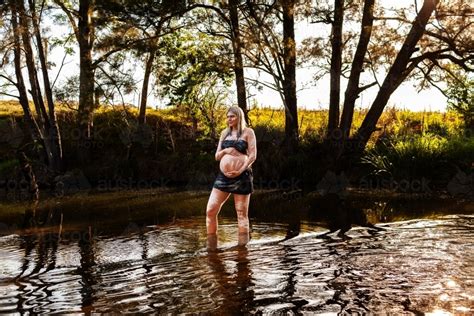 Image Of Wide Shot Of Aboriginal Australian Woman Standing In Creek