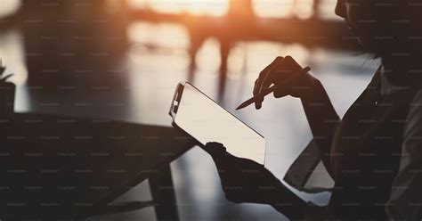 사무실에 앉아 디지털 태블릿을 들고 있는 사업가의 실루엣 사진 Unsplash의 디지털 태블릿 사용 이미지