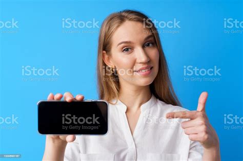 푸른 배경에 스마트 폰 화면을 보여주는 아름다운 젊은 여자 Brand Name Smart Phone에 대한 스톡 사진 및 기타