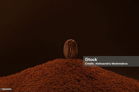 갓 구운 커피 콩은 갈색 배경에 한 줌의 분쇄 커피위에 서 있습니다 격리된 매크로 엽서 배너 공간을 복사합니다 갈색에 대한 스톡