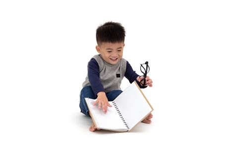 귀여운 아시아 의 어린 소년의 초상화 바닥에 앉아 흰색 배경 위에 고립 된 책을 읽고 학교 개념으로 돌아가기 1 년 10 개월