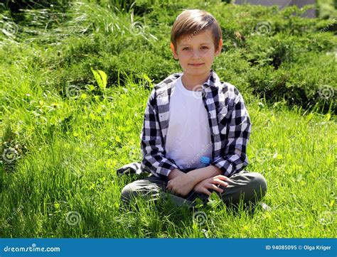 Милый белокурый мальчик сидит на траве Стоковое Изображение