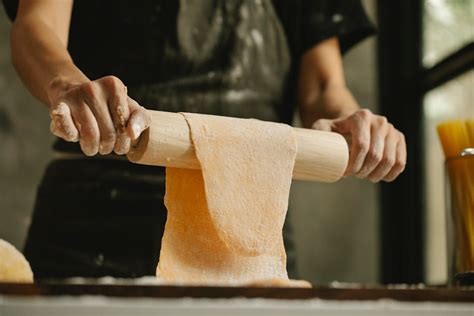 Молодая женщина раскатывающая тесто для выпечки на кухне · бесплатные