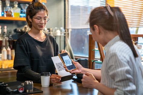 스마트폰을 스캔하는 바코드를 사용하여 비접촉식 결제를 하는 현대 아시아 여성은 커피숍에서 커피를 확인합니다 전자 모바일 뱅킹