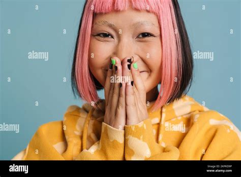 Asian Girl With Pink Hair Laughing And Covering Her Mouth Isolated Over Blue Background Stock