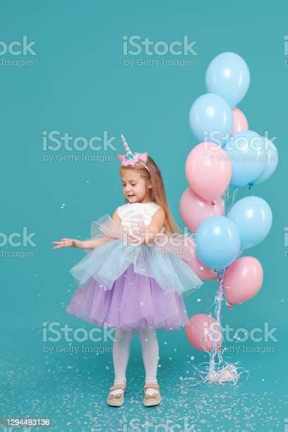 유니콘 소녀 우아한 튤 드레스와 유니콘 헤드 밴드를 입은 즐거운 어린이 소녀가 생일 파티를 축하하고 시안 배경에 여러 가지 색색