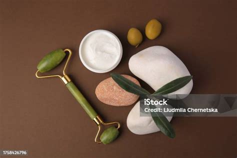 갈색 배경에 크림 얼굴 롤러 및 돌의 항아리를 가진 편평한 위치 구성 0명에 대한 스톡 사진 및 기타 이미지 0명 갈색