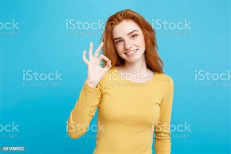 재미와 사람들 개념주 근 깨 웃 고 손가락으로 Ok 사인을 만드는 매력적인 생강 빨간 머리 여자의 얼굴만 초상화 파스텔 블루 배경입니다 공간에 복사 합니다 갈색 머리에 대한