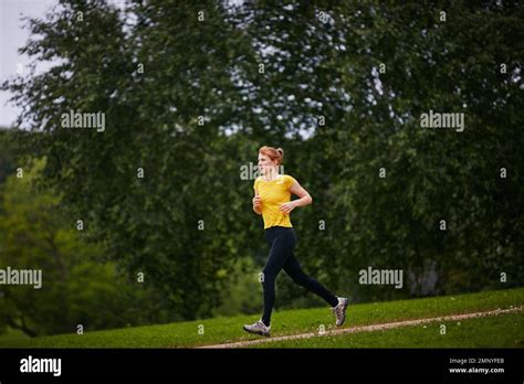 In It For The Long Run A Woman Jogging Along A Foothpath In A Park