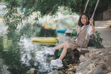 Premium Photo A Young Girl Is Swinging On A Rope Swing By A Body Of Water