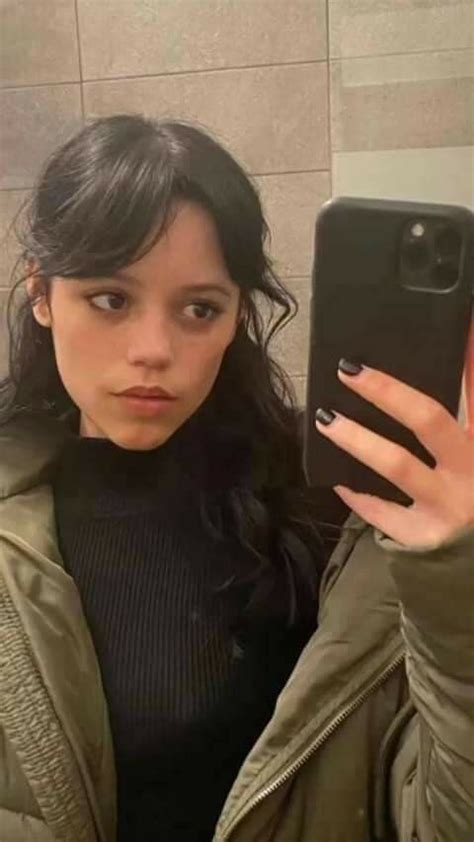 A Woman Taking A Selfie In Front Of Her Cell Phone While Wearing A