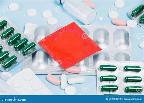 Medical Background A Condom In A Red Package An Ampoule And Pills On