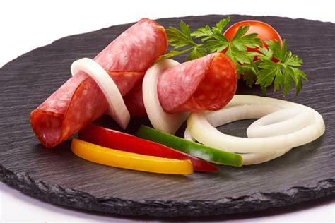 얇게 썬 매운 살라미 훈제 소시지 의 맛있는 전채 는 흰색 배경에 고립 된 돌 소박한 보드에 색깔이 가득한 야채 건조한에 대한