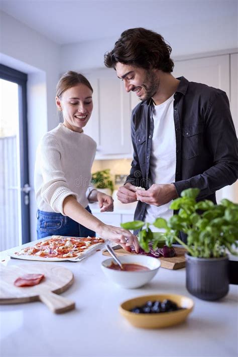 Couple In Kitchen At Home Making Homemade Pizza Together Stock Image