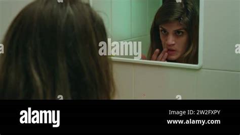 Young Woman Looking In The Mirror Discovering She Is Bleeding From Her Head Feeling Scared