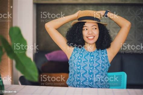 행복한 아시아 검은 곱슬 머리 여자는 모자를 쓰고 집 배경에 앉아 생각하고 35 39세에 대한 스톡 사진 및 기타 이미지 35 39세 감정 곱슬 머리 Istock