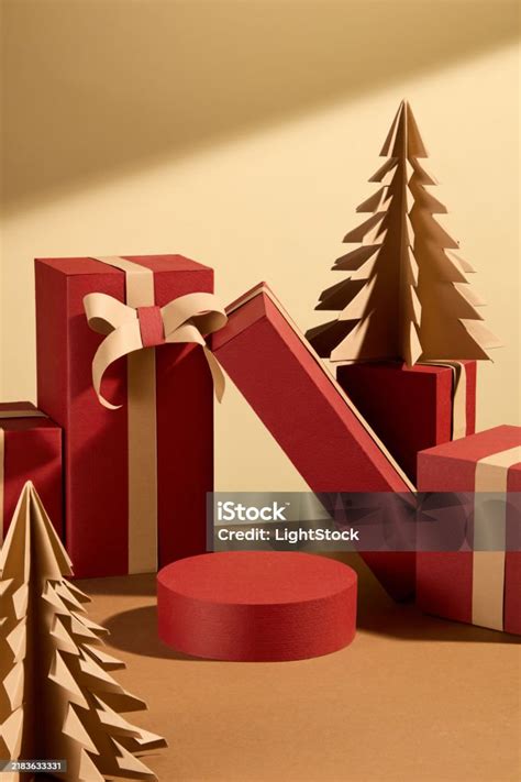 베이지색 배경에 크리스마스 테마 사진 템플릿에 대한 아이디어 갈색 표면에 제품 디스플레이를 위한 구형 빨간색 플랫폼의 클로즈업 그 뒤에는 빨간 선물 상자와 갈색 종이