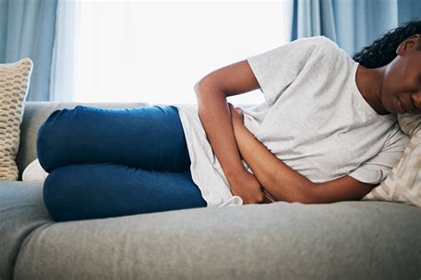 기간 복통 및 흑인 여성은 질병 경련 및 소화로 인해 배를 잡고 소파에 통증이 있습니다 월경 자궁 내막증 및 월경 문제가있는