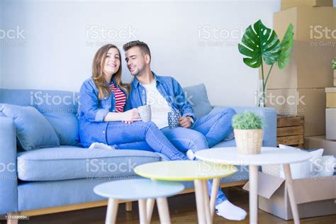 젊은 부부는 그들 주위에 골판지 상자와 함께 새로운 가정의 소파에 앉아 커피 한 잔을 마시고 새로운 아파트로 이동 매우 행복 2