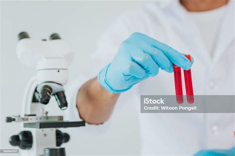 의사가 실험실에 있는 분석기가 있는 선반에서 혈액 샘플 튜브를 꺼냅니다 연구실에서 혈액 검사관을 들고 있는 기술자 Dna에 대한