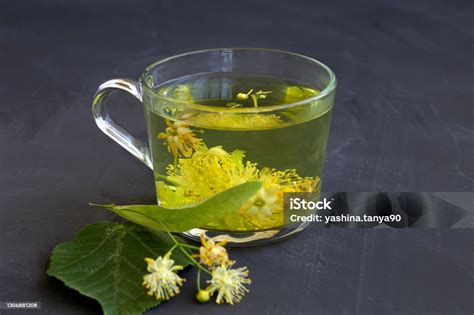린덴 꽃 차 검은 테이블에 린든 신선한 꽃뜨거운 허브 차 한 잔 건강한 라이프스타일녹색 잎이 있는 차 한 잔은 검은색 배경핫