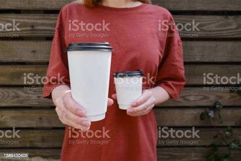 여성의 손에 커피와 흰색 종이 컵 도시에서 커피를 마실 시간입니다 커피갈기 순간을 즐기고 휴식을 취하십시오 일회용 종이 컵 클로즈업 맛있는 따뜻한 음료 텍스트 모형을 위한