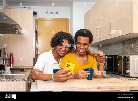 Gay Latin Adult Couple Sharing Mobile Phone While Drinking Morning