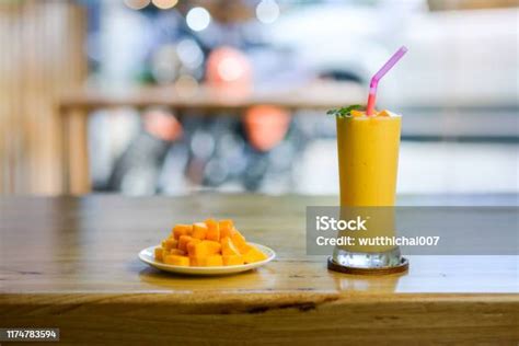 Smoothie Mangga Dalam Gelas Tinggi Dengan Sepiring Mangga Yang Dicedup