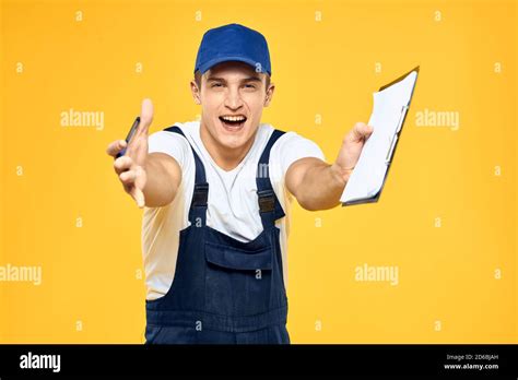 Man In Working Uniform Documents Rendering Of Services Delivery Service Yellow Background Stock