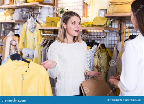Two Smiling Young Women Friends Talking In Clothes Showroom Stock Image