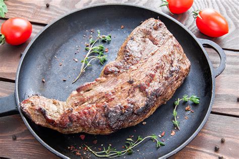 허브와 향신료와 빨간 체리 토마토와 피망 사금에서 갈색 나무 테이블에 검은 철 프라이팬에 백 리 향의 잔 가지와 함께 뿌 렸 다