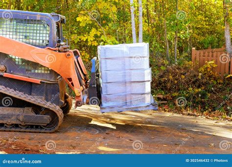 Worker Is Unloading Pallets Of Concrete Blocks For Retaining Wall While