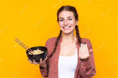 Premium Photo Girl Holding A Bowl Full Of Noodles Over Isolated Wall