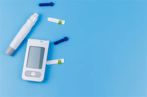 파스텔 블루 배경에 디지털 글루코프 랜싯 펜 일회용 바늘 및 테스트 스트립 상단 보기 복사 공간 당뇨병 개념 개념에 대한 스톡