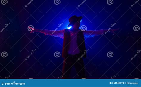Man Musician In Stylish Hat Dancing On Dark Concert Stage Against Blue