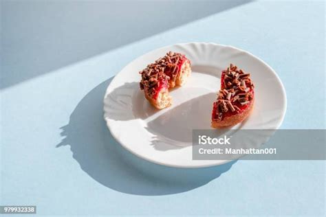 ドーナツ半分赤釉に青の背景に白い皿にすりおろしたチョコレートを振りかけた おやつのストックフォトや画像を多数ご用意 おやつ