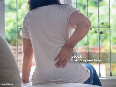 집에서 소파에 앉아 그녀의 뒤에 젊은 여자 느낌 고통 의료 및 의료 개념입니다 허리통증에 대한 스톡 사진 및 기타 이미지