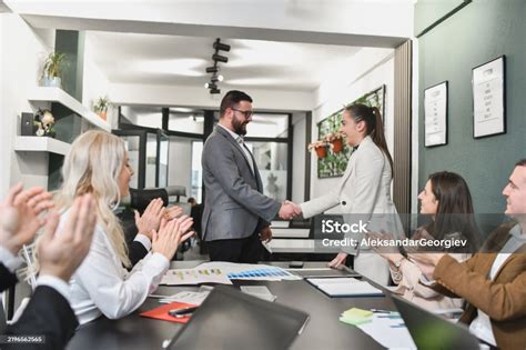 남성과 여성이 팀원들이 박수를 보내는 동안 Handshake로 비즈니스 파트너십을 확인합니다 계약서에 대한 스톡 사진 및 기타 이미지 Istock