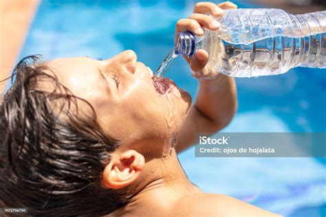 더운 여름날 수영장에서 플라스틱 병으로 물을 마시는 소년 열사병을 피하기 위해 운동 후 물을 많이 마시는 청년 운동 후 물을 많이 마시는 아이 아이에 대한 스톡 사진 및