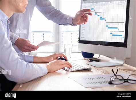 Project Management Team Updating Gantt Chart Schedule Or Planning On Computer Two Business