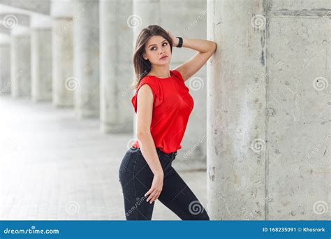 Beautiful Woman In Red Blouse And Jeans Posing While Leaning On Gray Column Stock Image Image