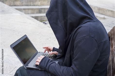 Foto De Dangerous Babe Hacker Breaking A Secret Code With His Laptop Sitting On A Bench Outside