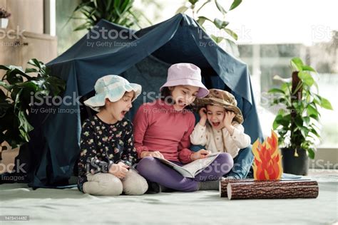두 명의 어린 소녀와 한 명의 유아 소년이 캠핑 게임을 하고 집에서 책을 읽고 아이들을 위한 집에서 활동을 위한 활동 개념 10