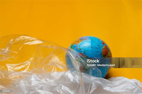 環境汚染コンセプトにおける黄色の背景に白いフィルムプラスチックゴミの青い世界モデル グローバルのストックフォトや画像を多数ご用意