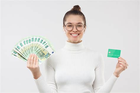 유로 지폐와 신용 카드의 팬을 들고 안경을 쓴 젊은 여성 지불 방법 중 선택 행복하게 미소 회색 배경에 고립 100에 대한 스톡
