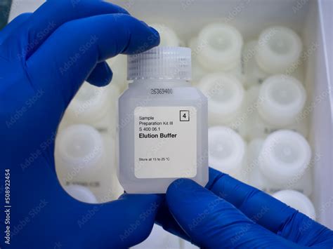Close Up Two Hands In Blue Gloves Hold A White Chemical Reagent Bottle