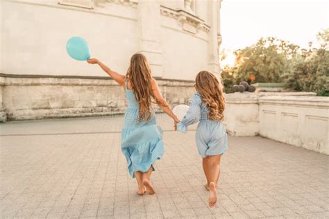 Hija Madre Corriendo De La Mano En Vestidos Azules Con El Pelo Largo