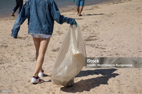 환경과 생태를 보호하기 위해 큰 비닐 봉지에 플라스틱 쓰레기와 쓰레기를 집어 들고 여름에 는 젊은이와 십대 운동가와 지역 사회의 사람들이 더러운 해변을 청소하고 있습니다